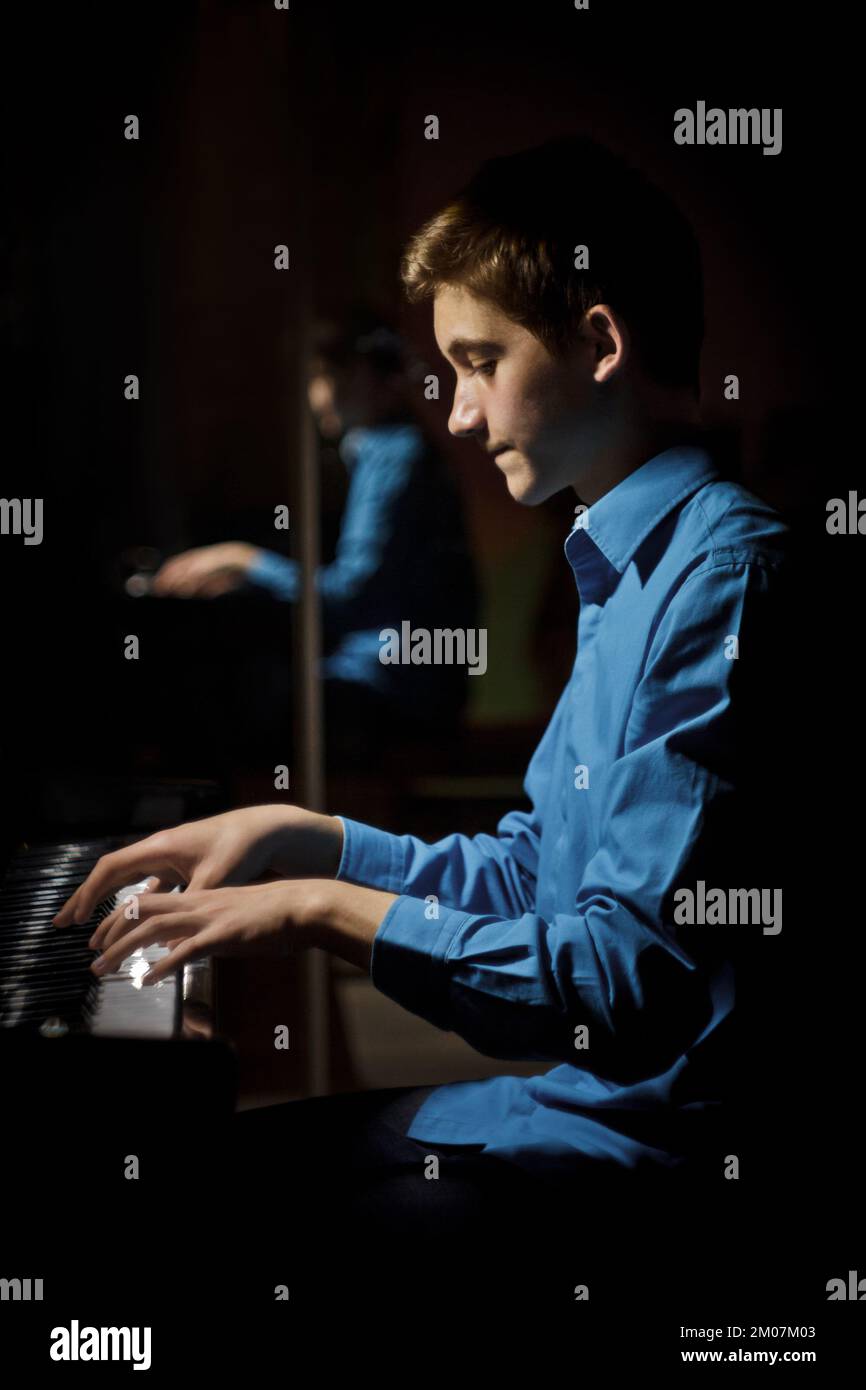 young man sitting at the piano. boy emotionally plays the keyboard ...