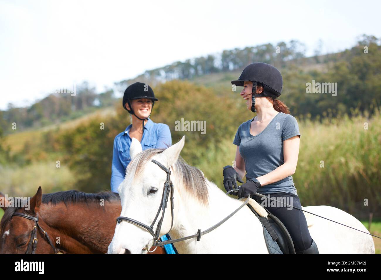 Enjoying riding their horses out in the open fields. Two young women ...