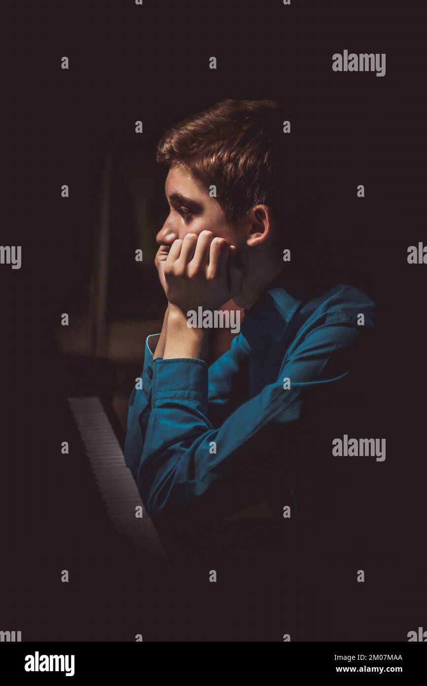 young man sitting at the piano. the boy wondered how he played the ...