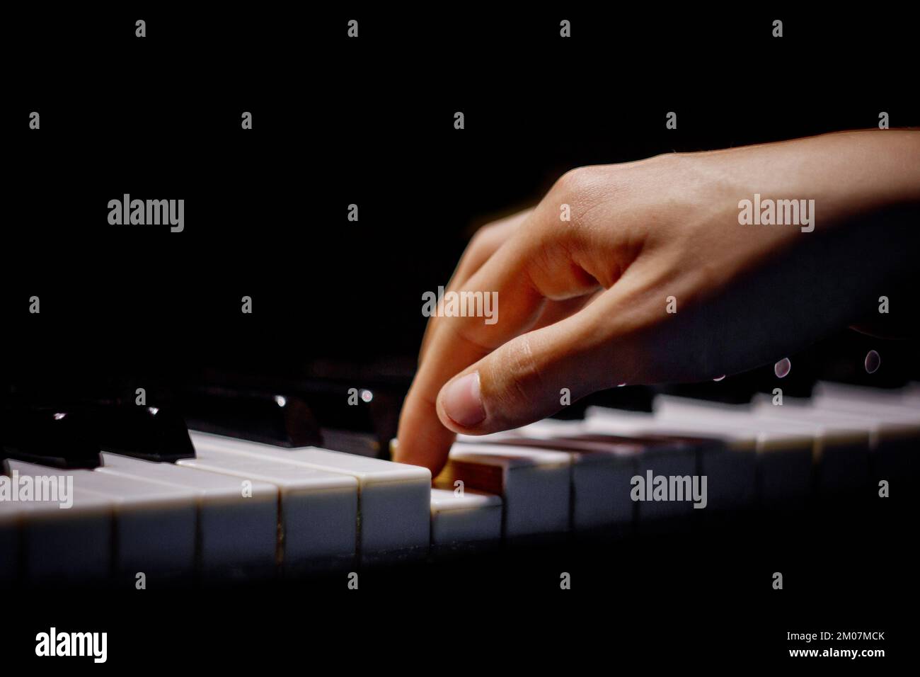 one male hand on the piano. The palm lies on the keys and plays the ...