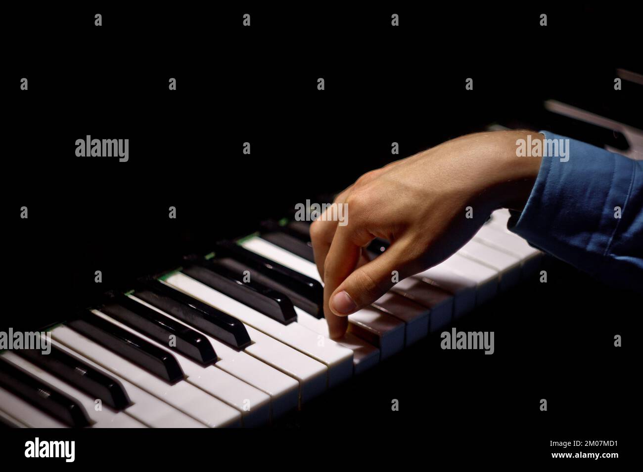one male hand on the piano. The palm lies on the keys and plays the ...