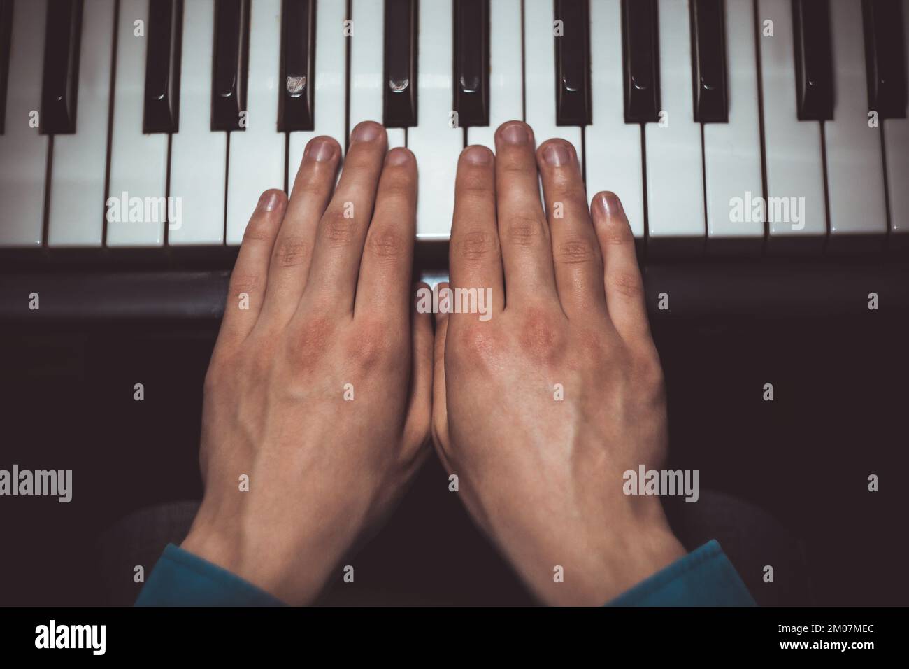 two male hands on the piano. palms lie on the keys and play the ...