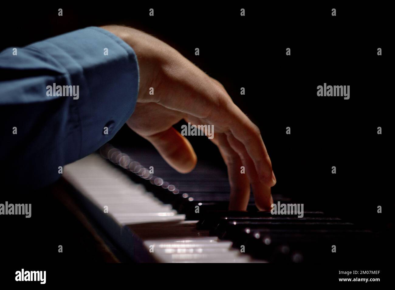 one male hand on the piano. The palm lies on the keys and plays the ...