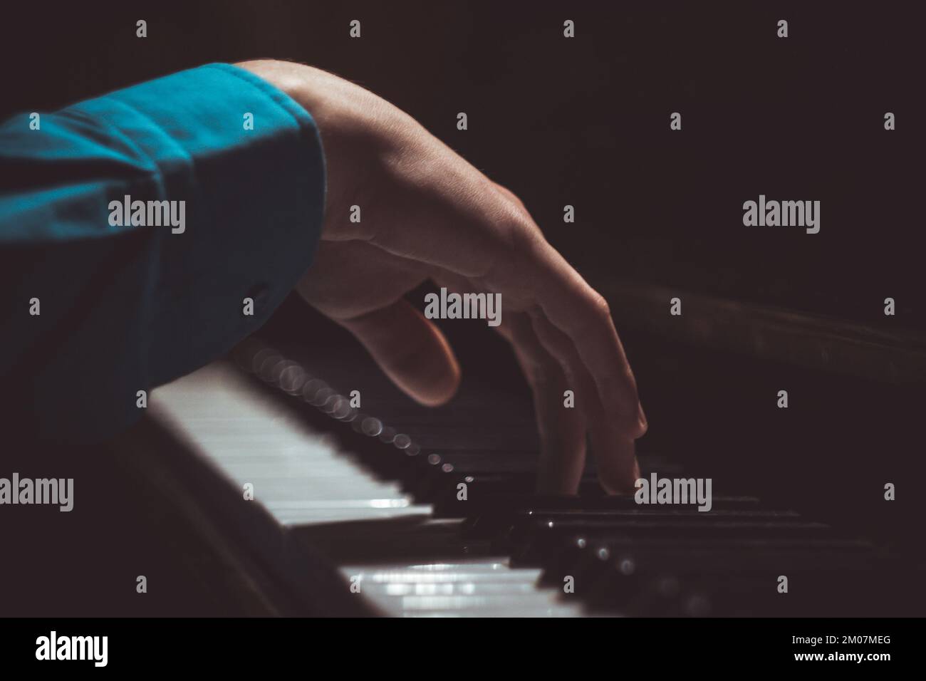 one male hand on the piano. The palm lies on the keys and plays the ...