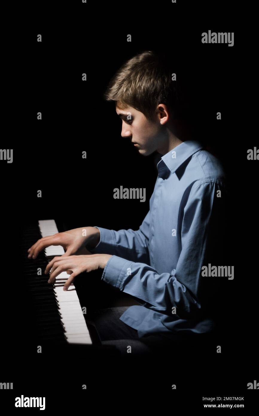 young man sitting at the piano. boy emotionally plays the keyboard ...