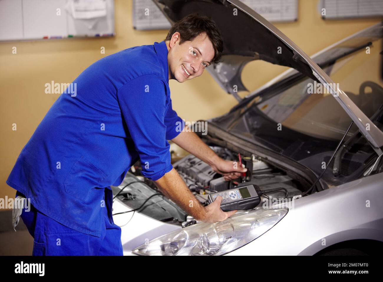 Your new battery has been fitted. Portrait of a male mechanic measuring ...
