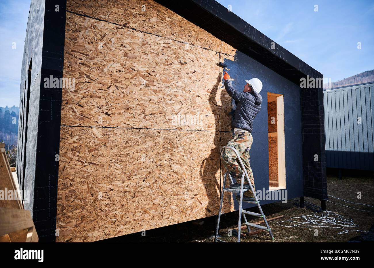 Male painter using paint roller, doing exterior paint work in a black ...