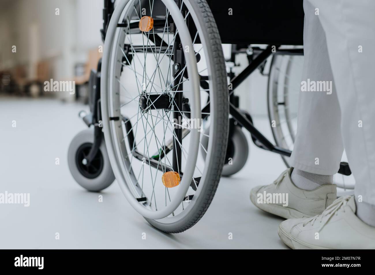 Rear view of caregiver pushing wheelchair at hospital corridor Stock ...