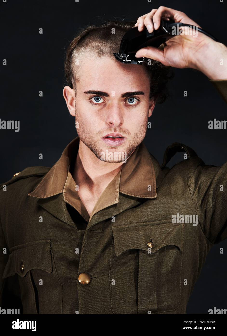 Time for a change. Portrait of a young man in military uniform shaving ...