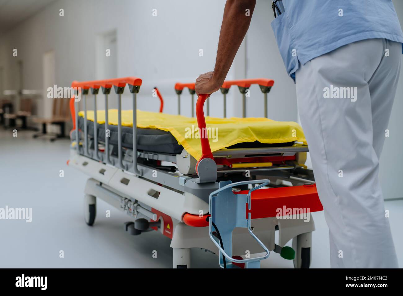 Rear view of caregiver pushing hospital bed at corridor Stock Photo - Alamy