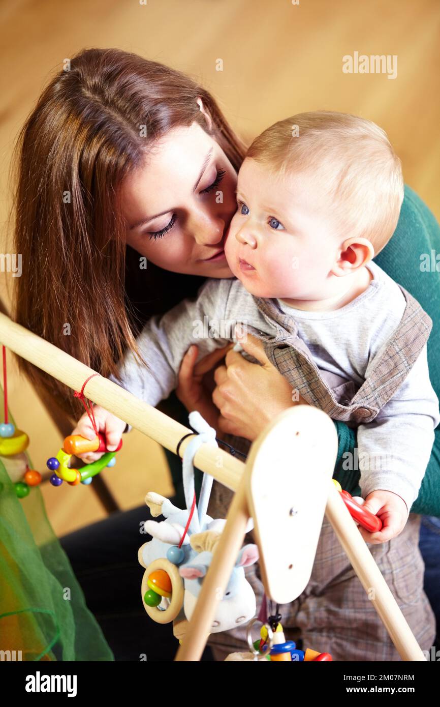 Hes so precious. Young mom giving her baby a cuddle while he plays ...