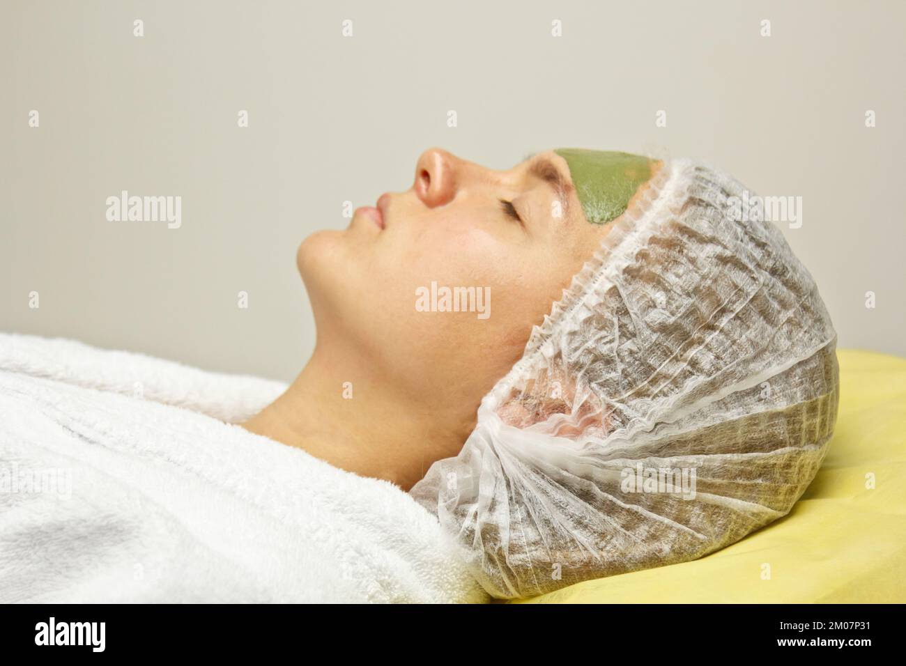 The concept of cosmetology. Close-up of a beautician applying a green ...