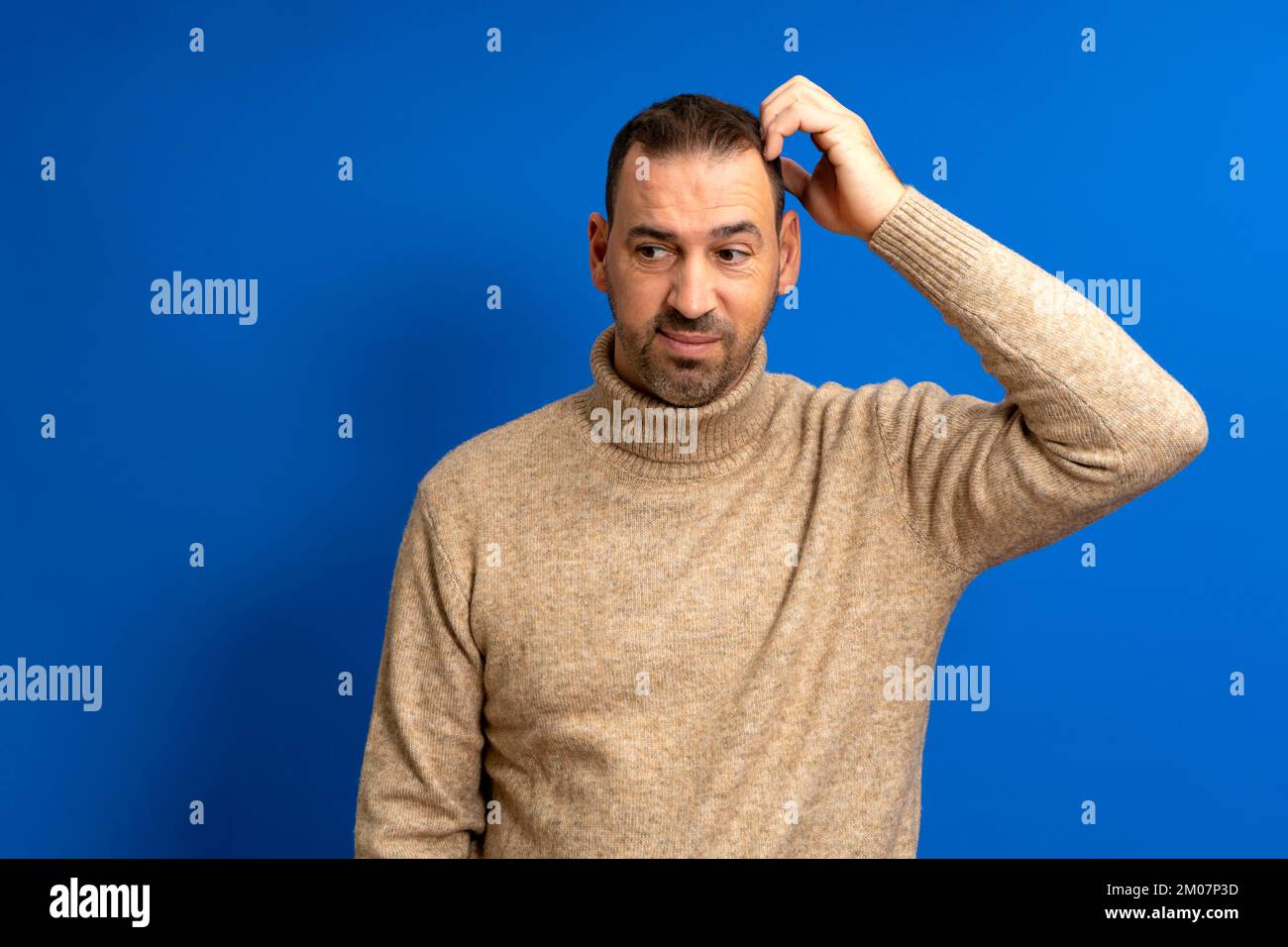Doubtful bearded latin man thinking, scratching his head and trying to ...