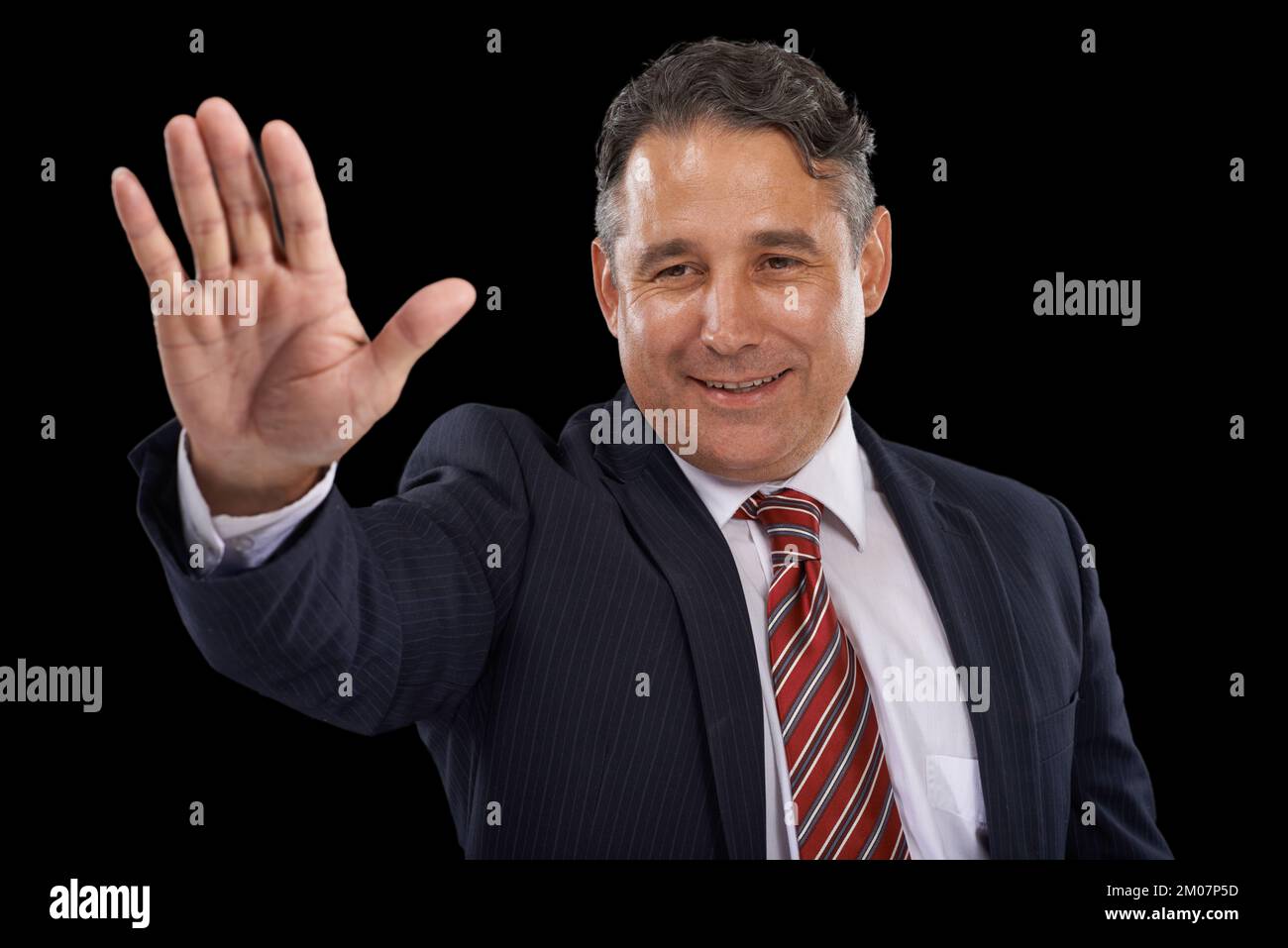 Greeting you with a wave. A man in a suit waving on a black background ...