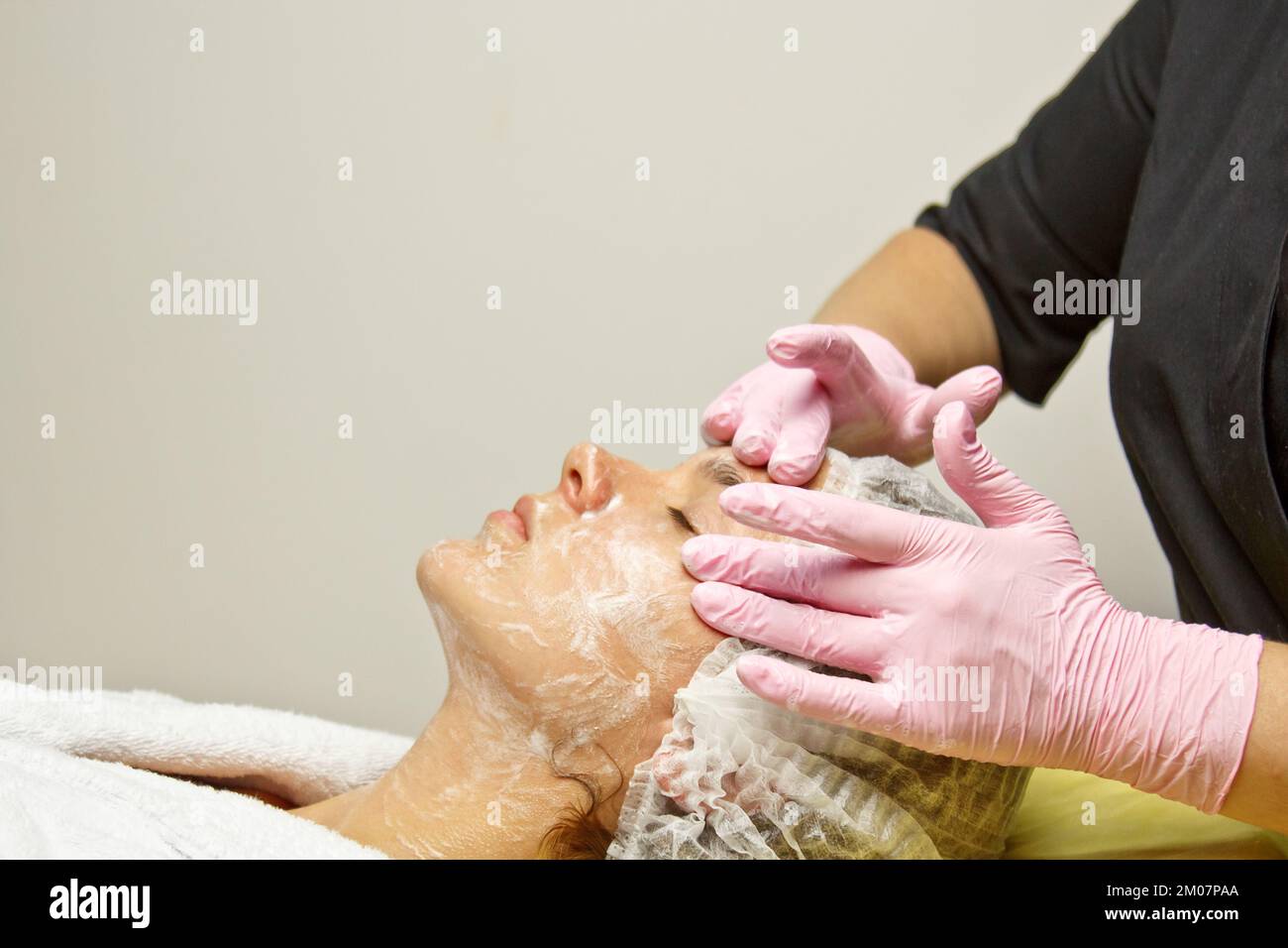 concept beautician. The hands of a cosmetologist put cream on the face ...