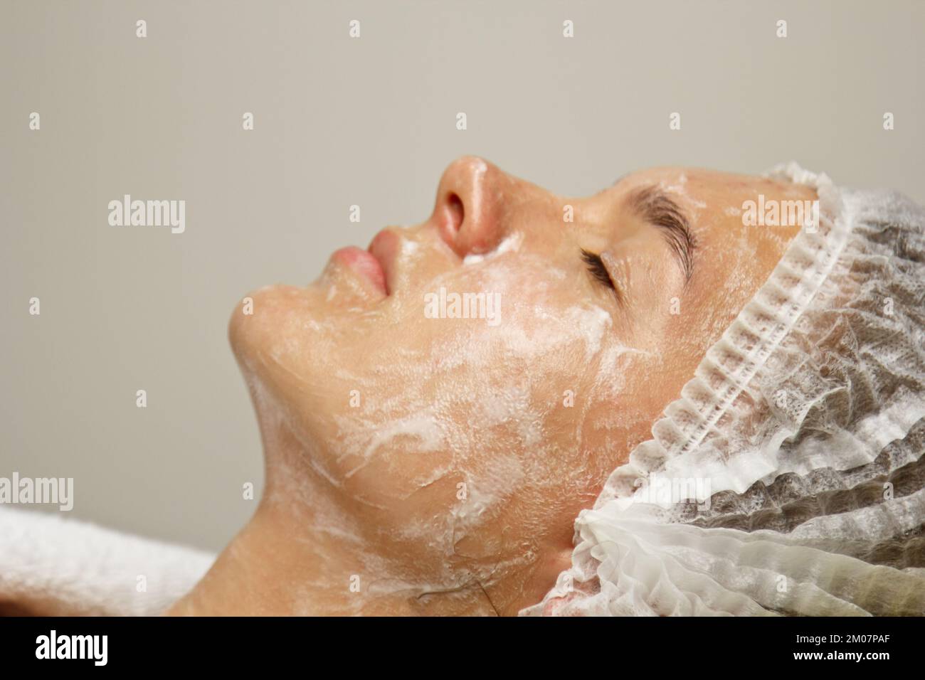 concept beautician. The hands of a cosmetologist put cream on the face ...