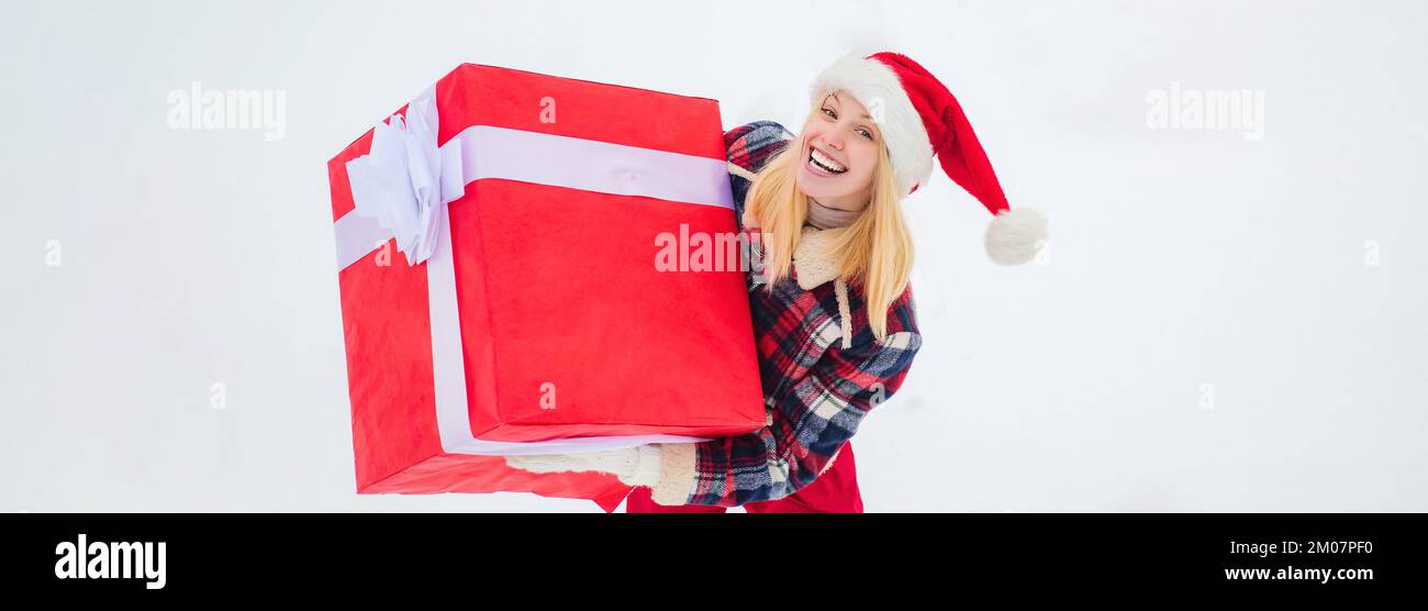 Winter delivery service. Woman carrying a big present isolated on snow ...