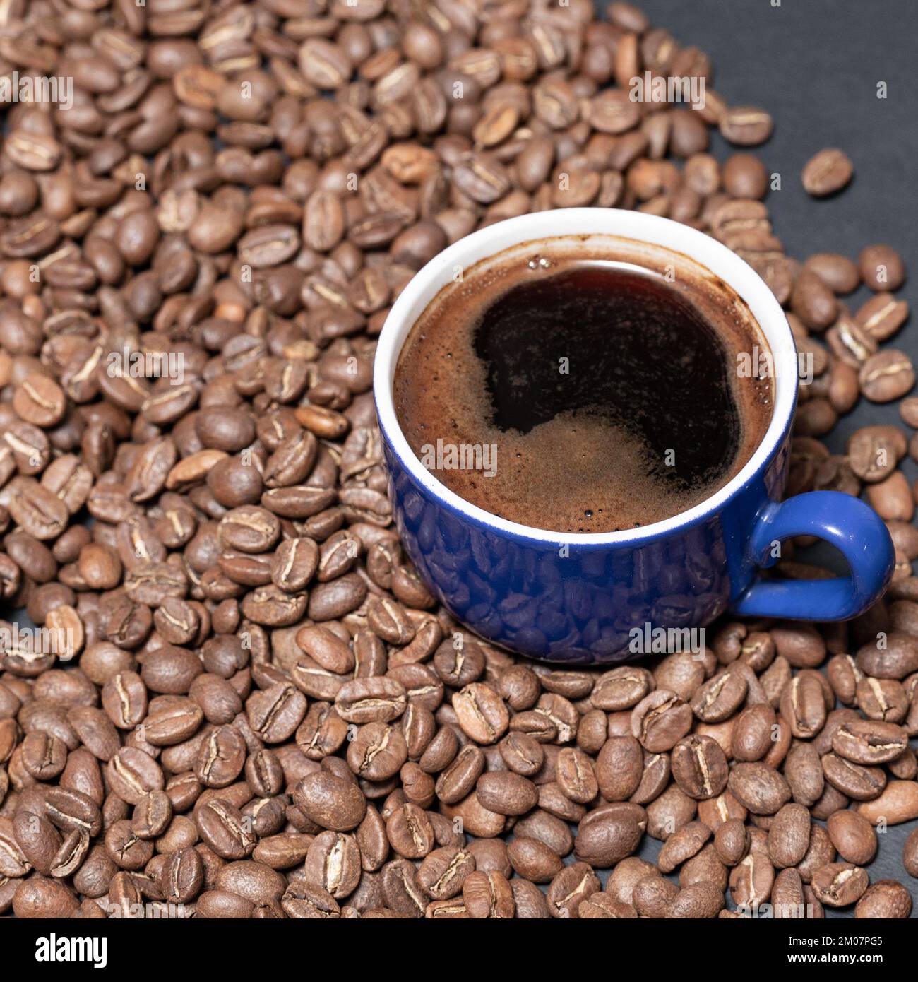 A cup of brewed black coffee on a dark background with beans, light ...