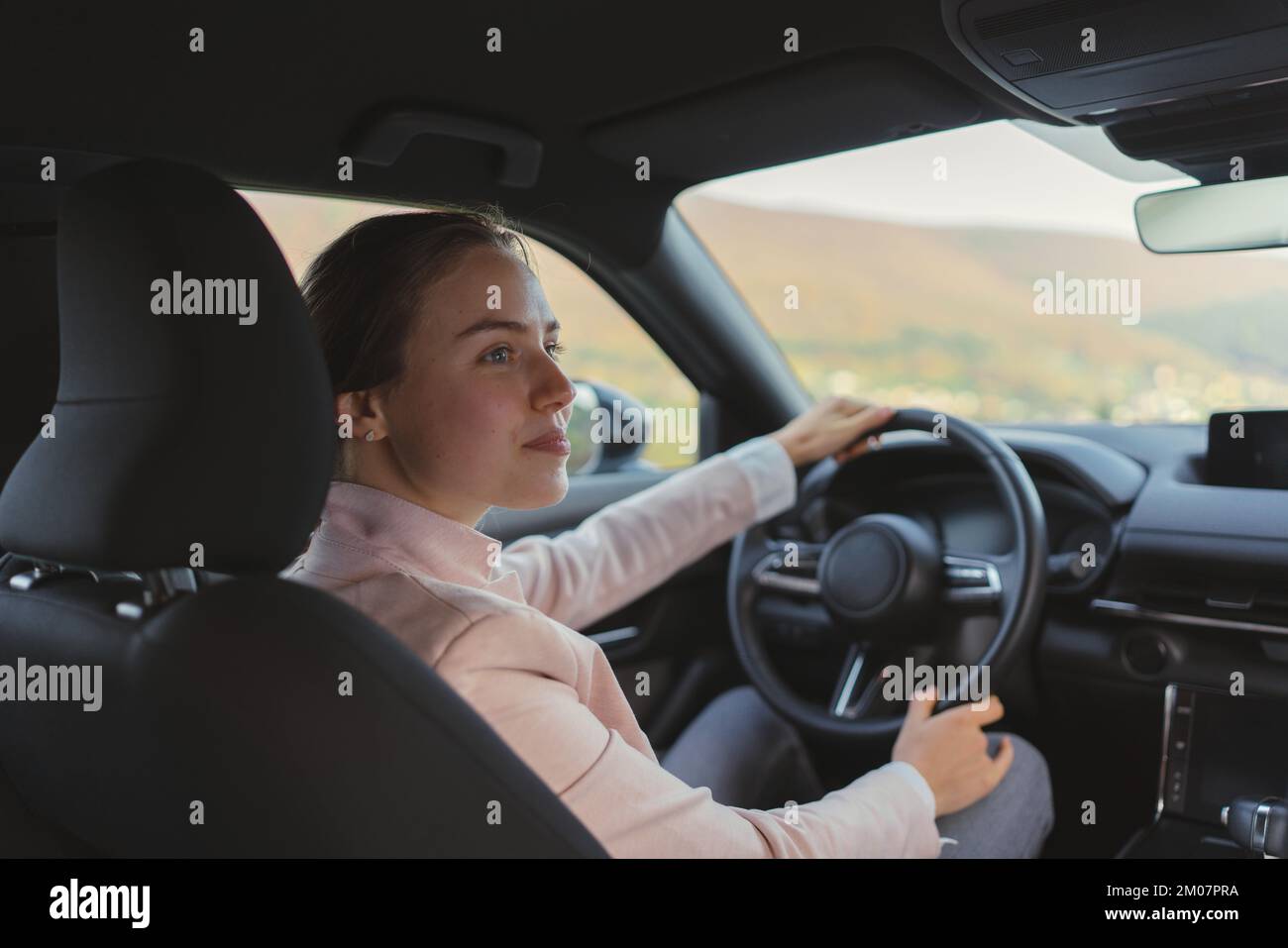 Excited young woman driving her electric car Stock Photo - Alamy