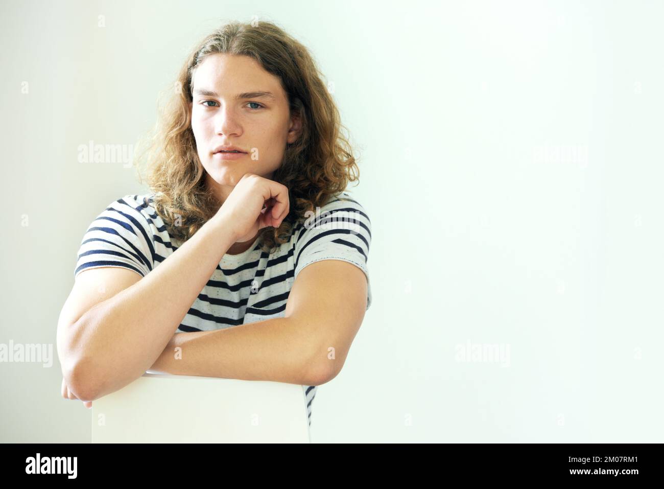Thinking things over. Casual young man with long, curly hair leaning on a backwards chair Stock ...