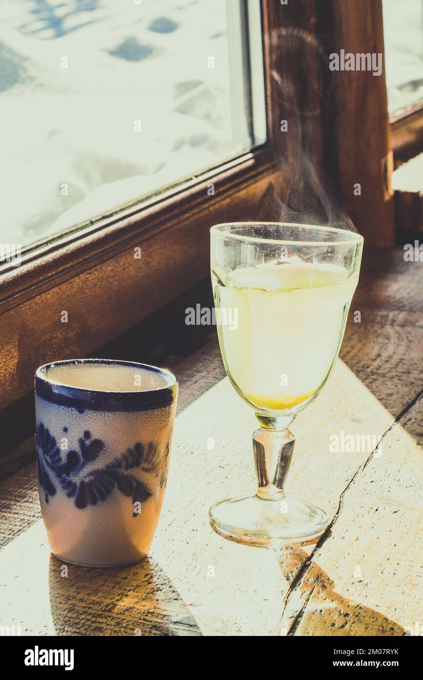Close up mug and glass with hot drink on window sill concept photo ...