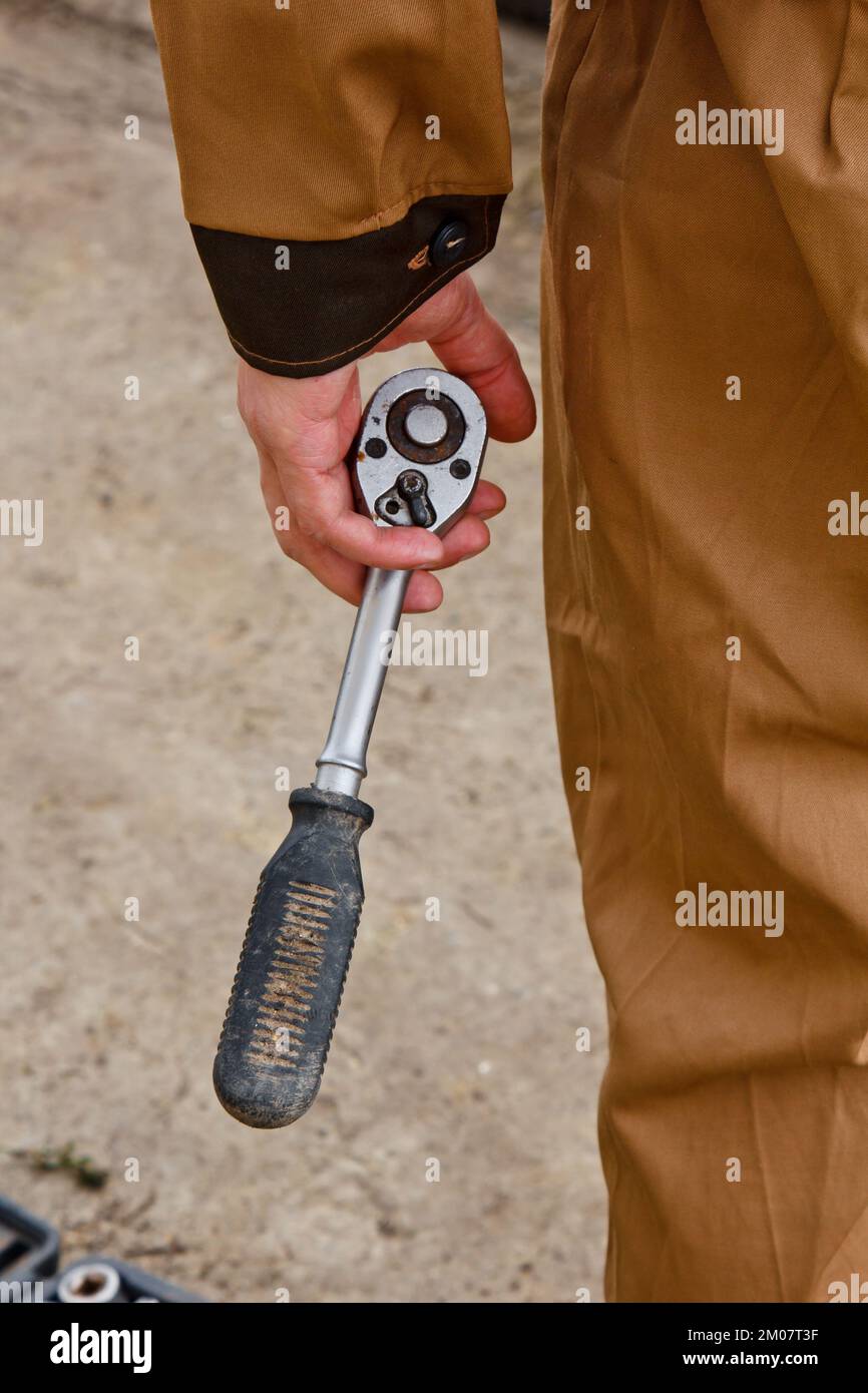Auto mechanic man with electric screwdriver changing tire outside. Car ...