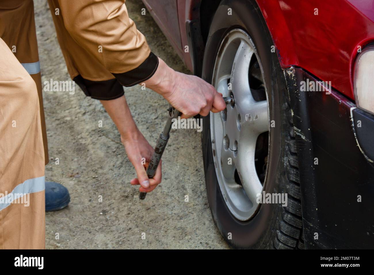 Auto mechanic man with electric screwdriver changing tire outside. Car ...