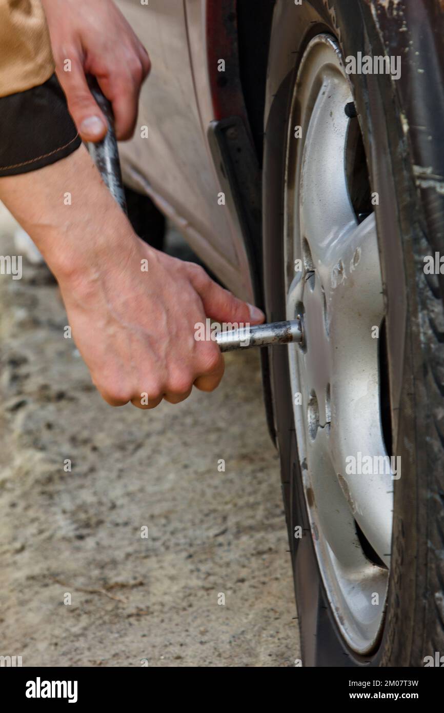 Auto mechanic man with electric screwdriver changing tire outside. Car ...