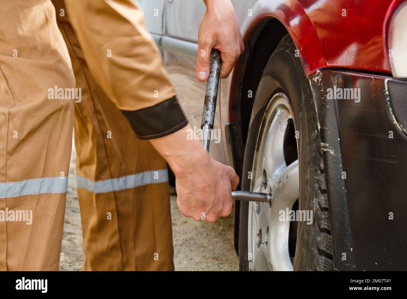 Auto mechanic man with electric screwdriver changing tire outside. Car ...