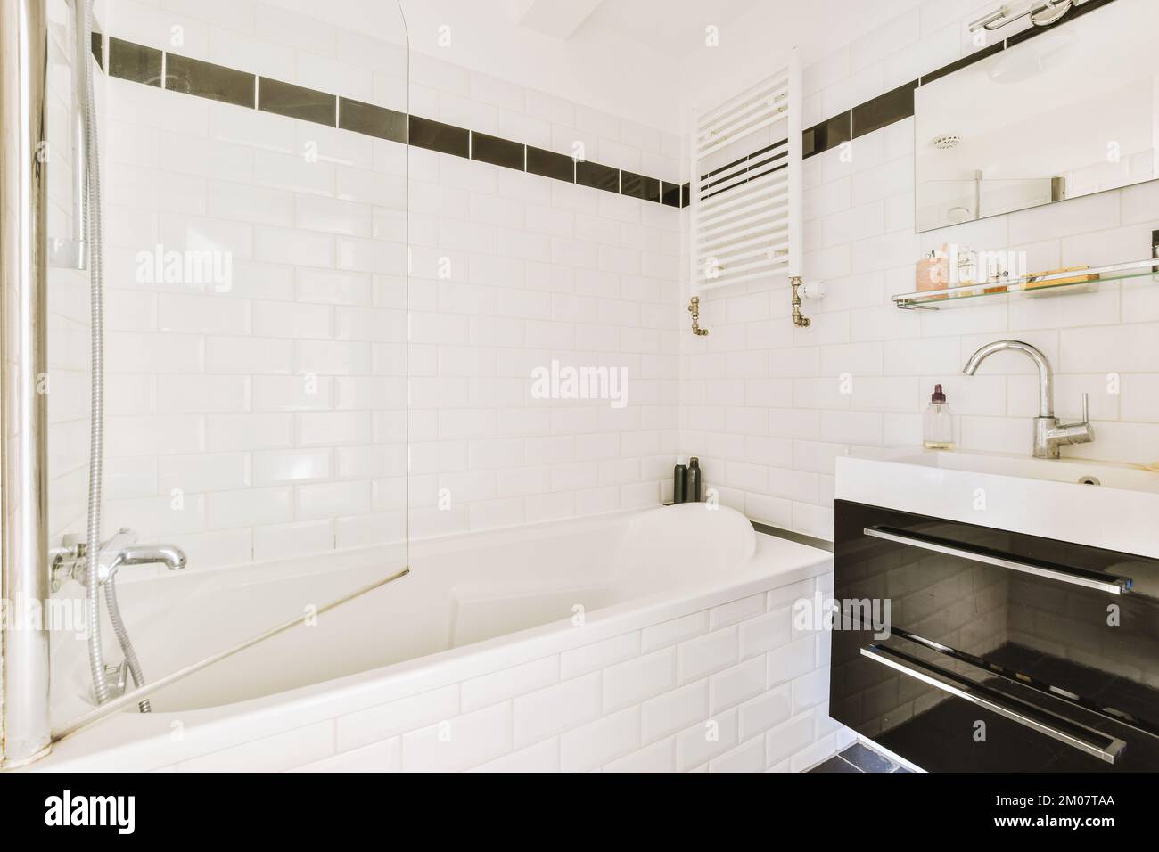 Flush toilet located between sink and shower in small tiled bathroom of ...