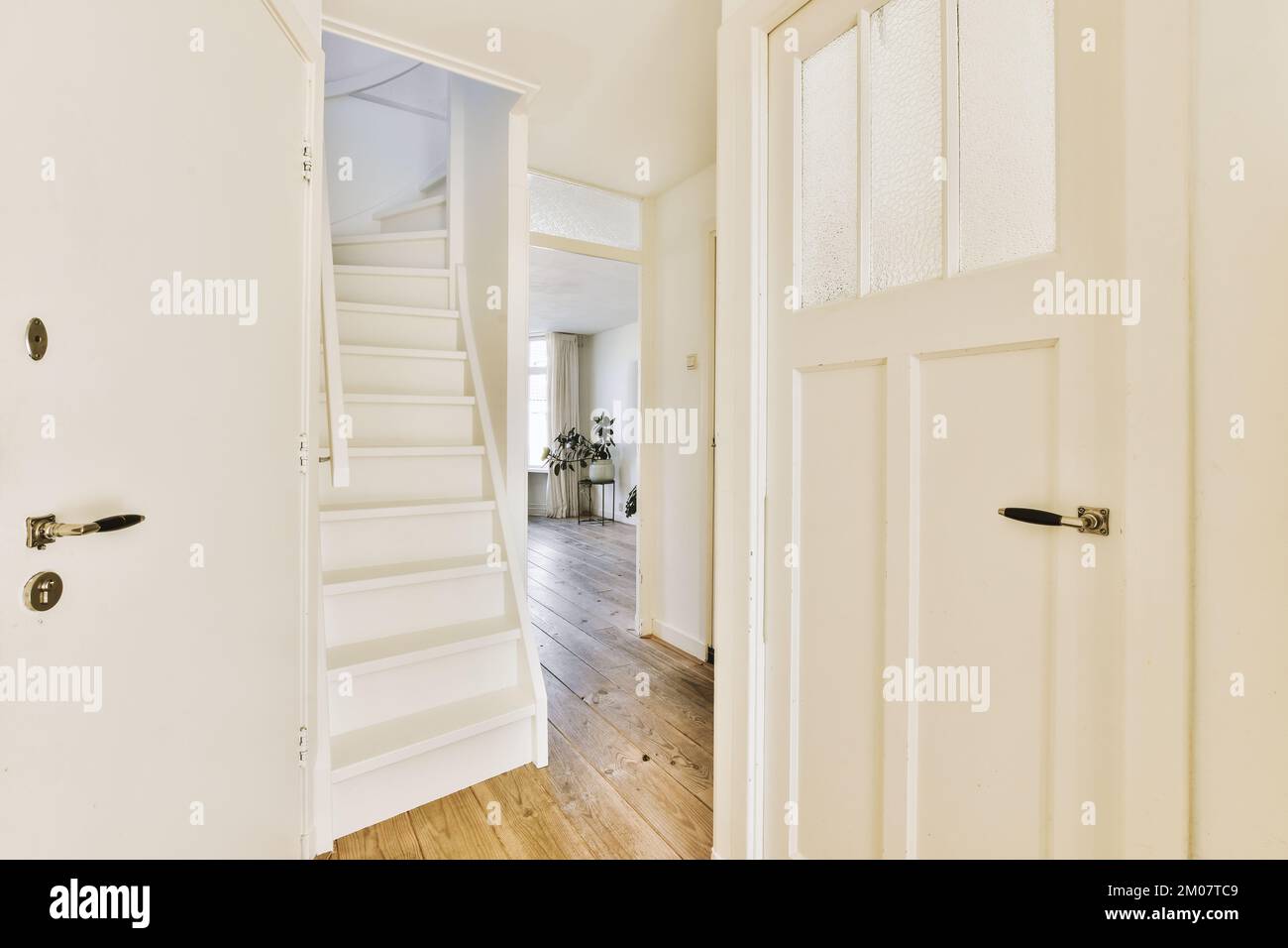 White hallway with wooden stairway leading to second floor of modern ...