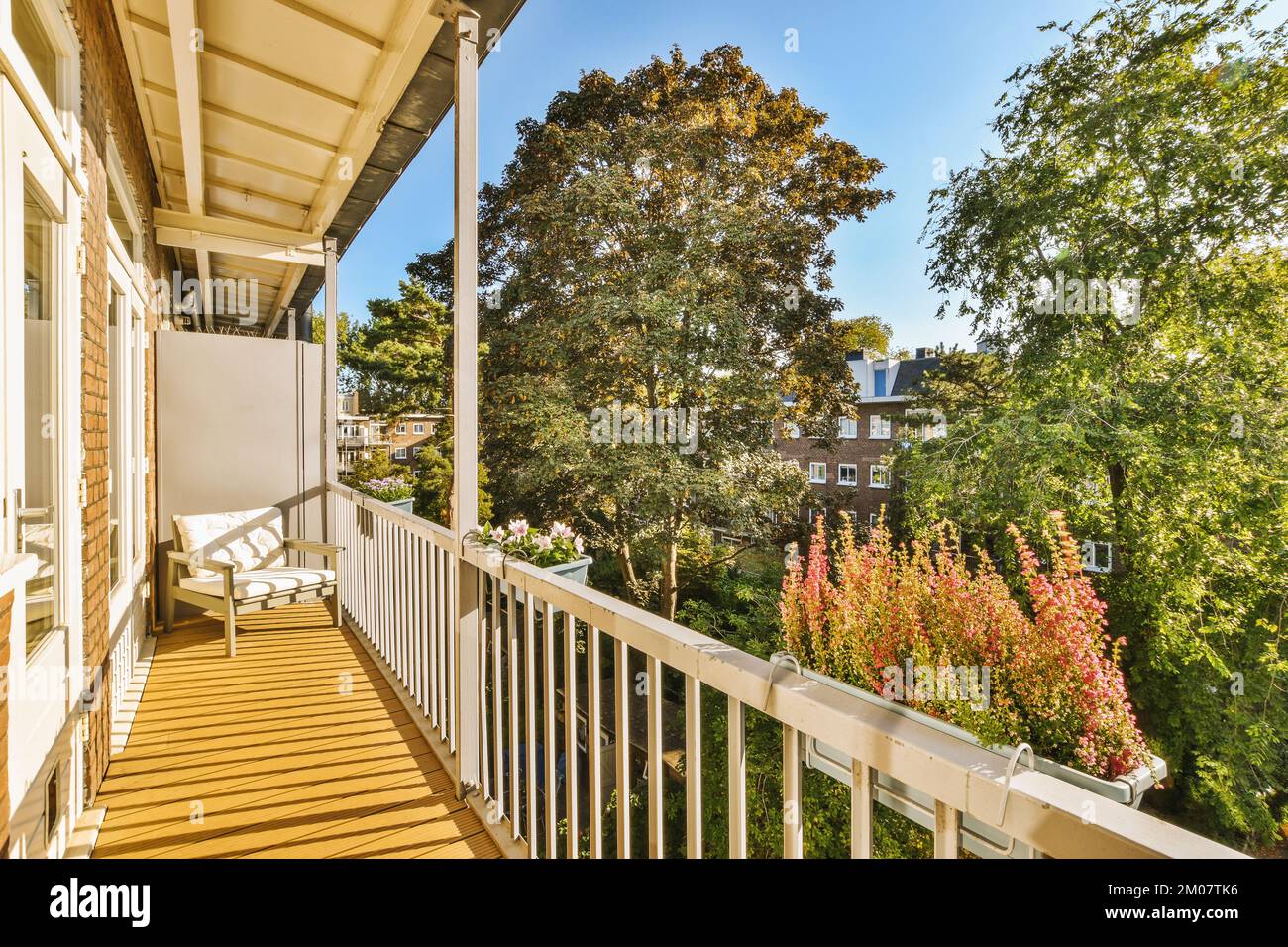 Narrow brick balcony with metal railings, wooden chair and door with ...