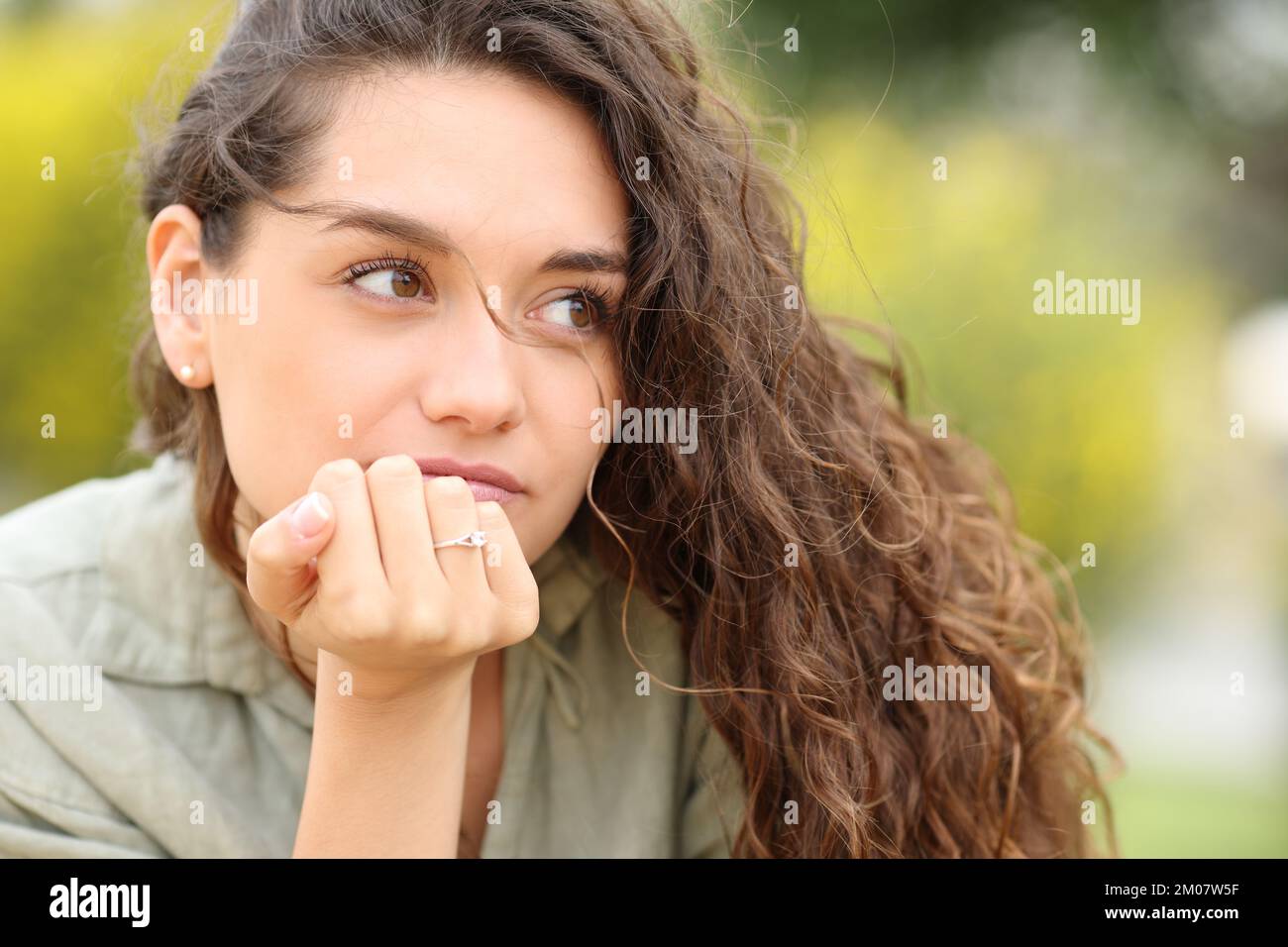Serious woman with engagement ring looks away in a park Stock Photo - Alamy