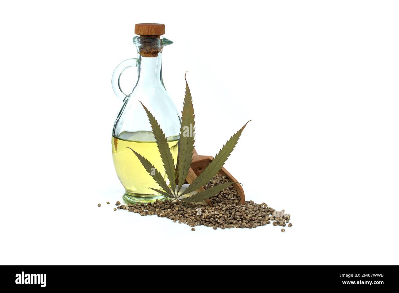 Hemp leaf in front of cannabis oil in glass decanter and hemp seeds ...