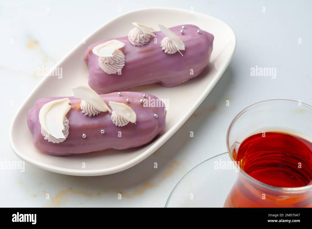 Two eclair cakes with violet frosting on white plate Stock Photo - Alamy