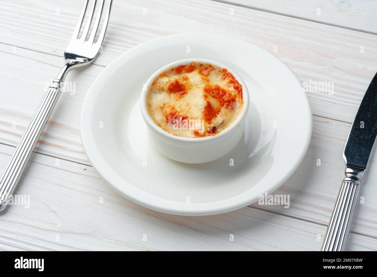 Baked julienne with mushrooms and cheese on top on white plate Stock ...