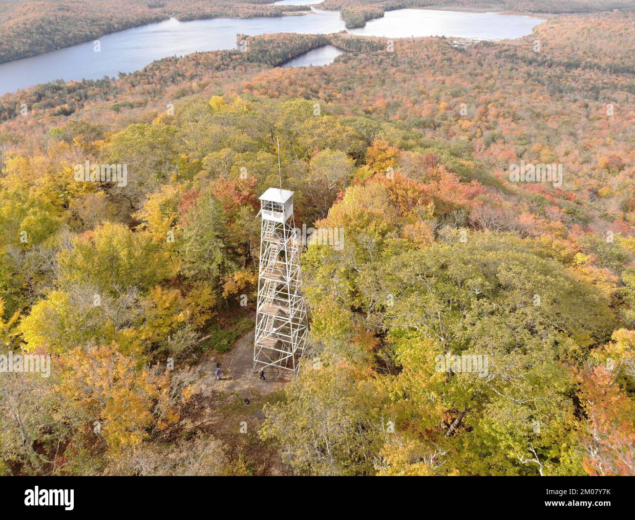 An aerial of Kane Mountain Fire Tower with autumn forest scape water ...