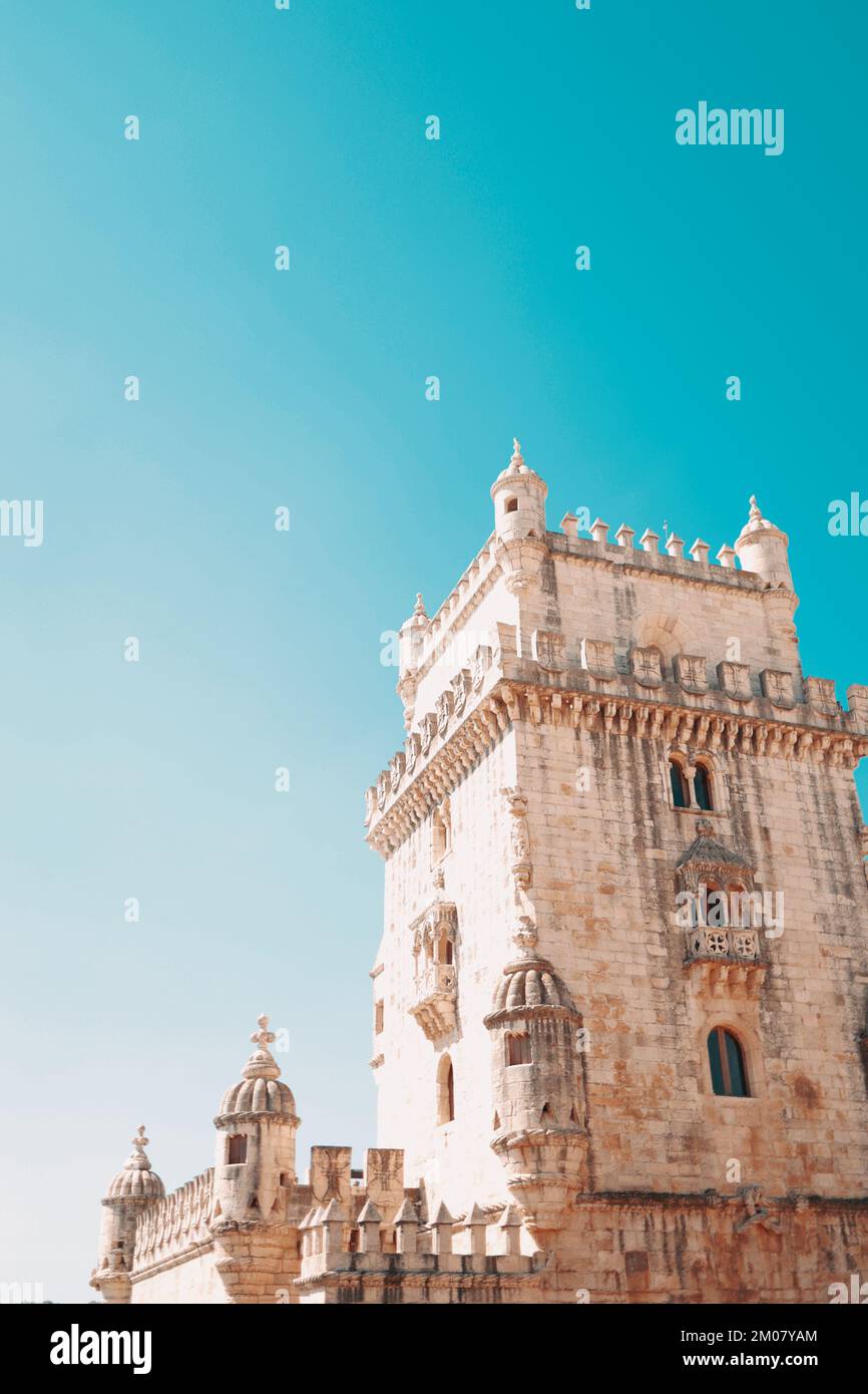 A low-angle vertical of Belem tower fortification clear sunlit sky ...