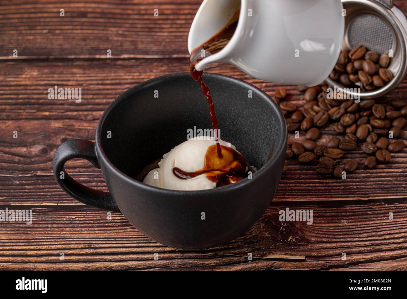 Espresso with ice cream in black porcelain cup on wooden table ...
