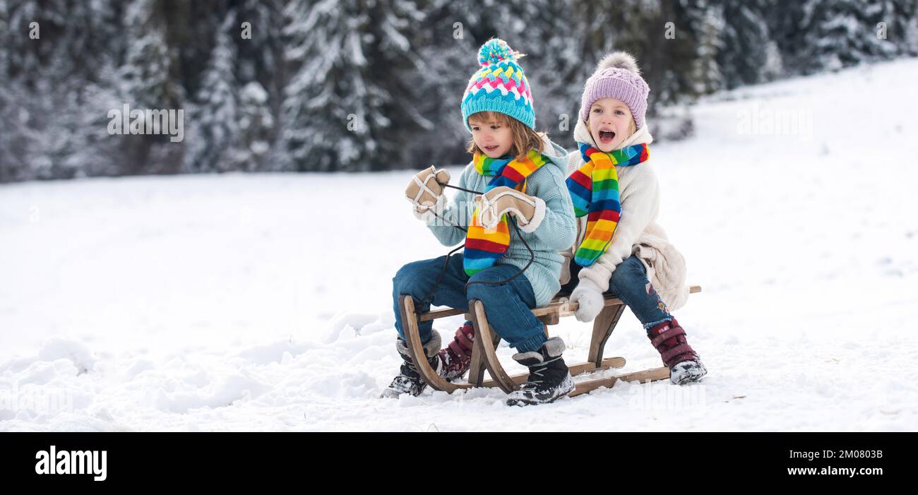 Kids ride on a wooden retro sled on a winter day. Active winter ...