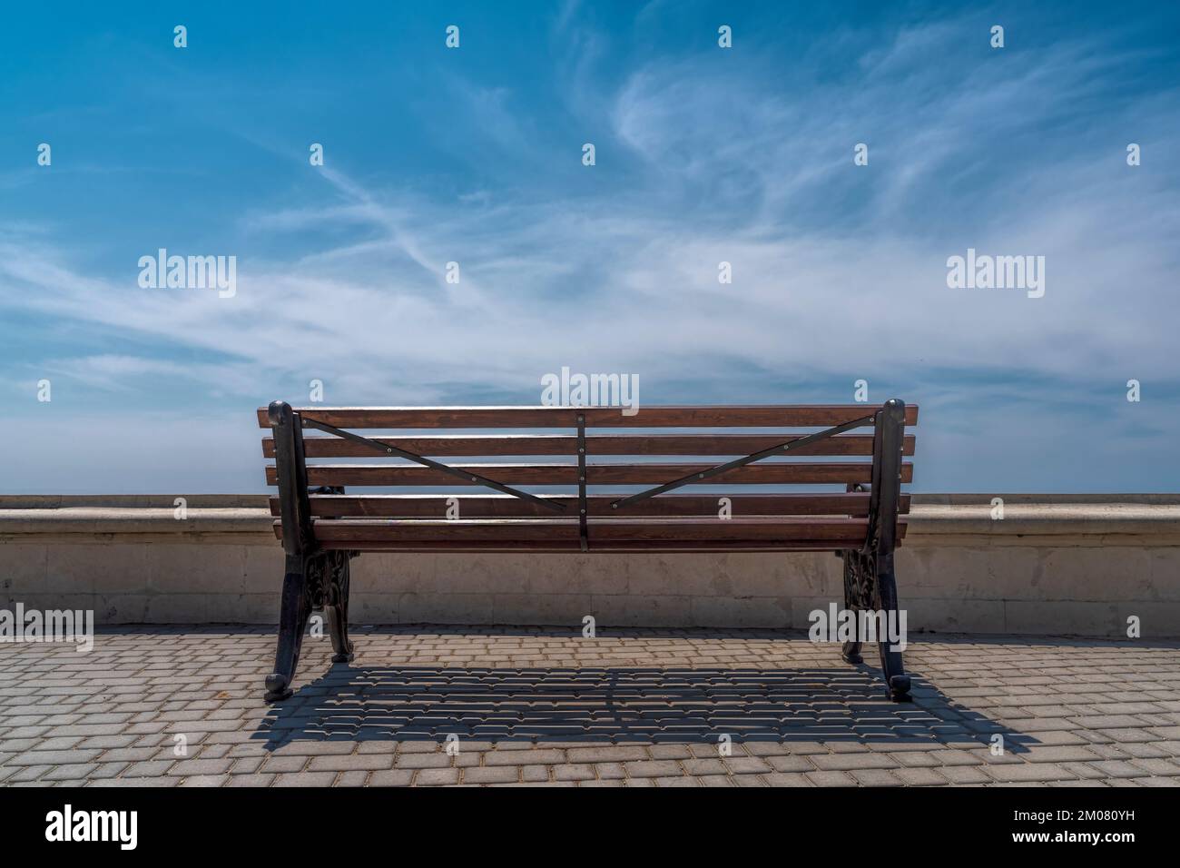 An empty bench against the background of blue sky and clouds in the ...