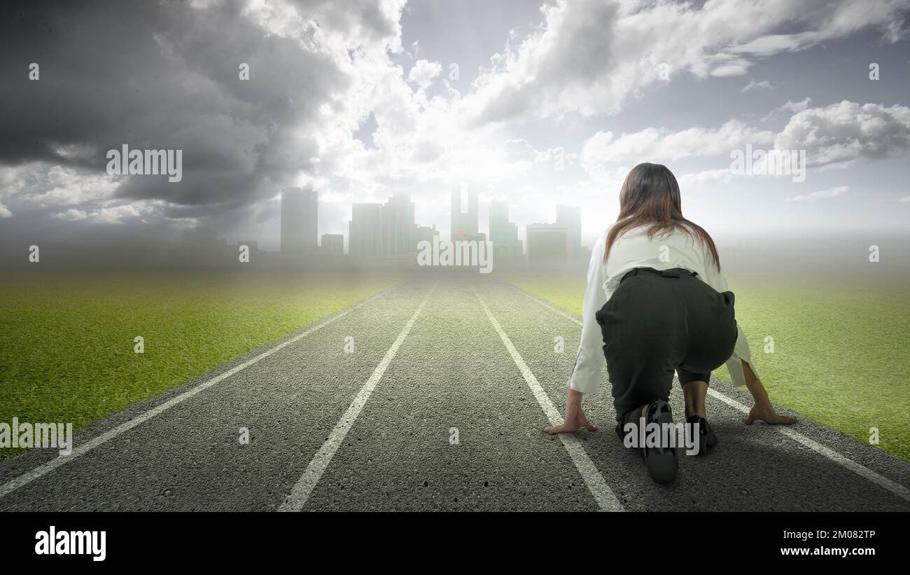 Rear view of Asian businesswoman in start position ready to run on the ...
