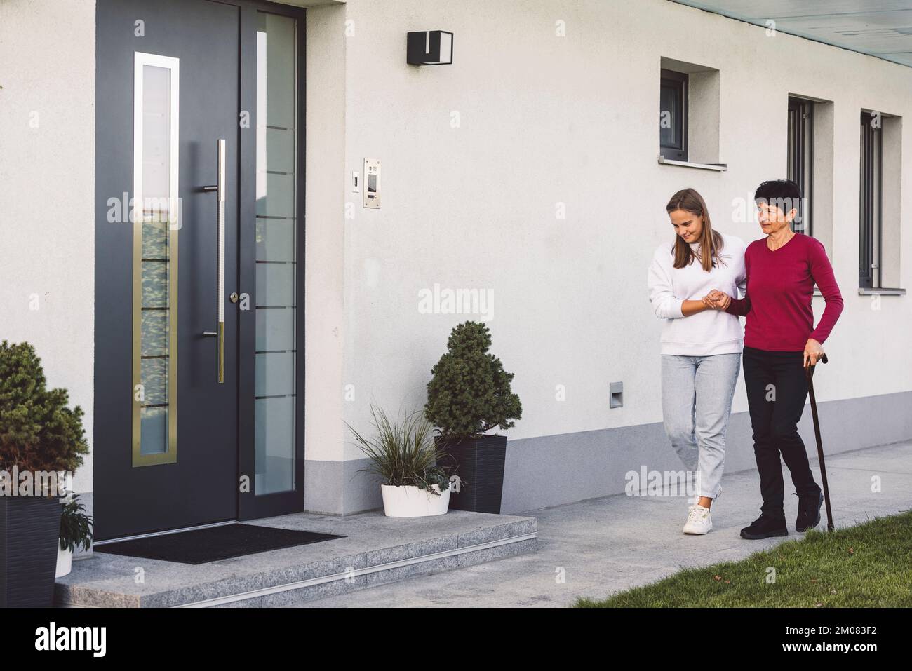 Nurse holding a senior lady for her hands helping her to walk to the ...