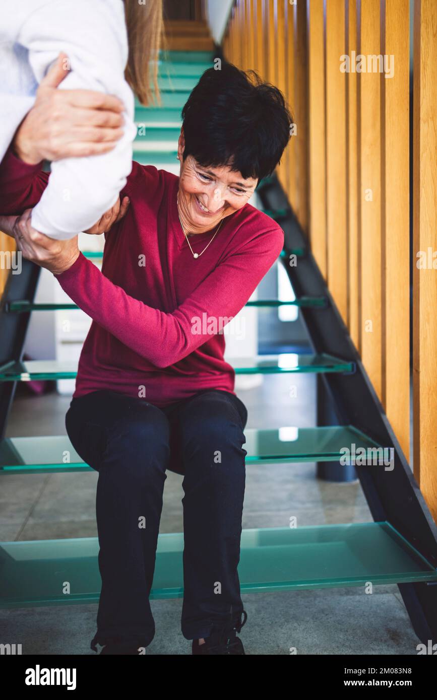 Senior woman grabbing for nurses arm to help her stand up from the ...