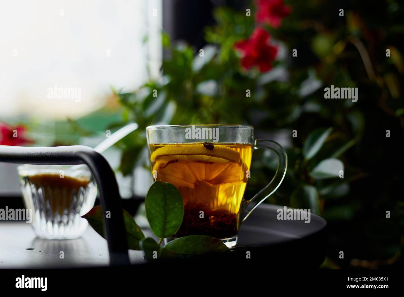 Glass cup of hot black tea lemon on dark background with steam near ...