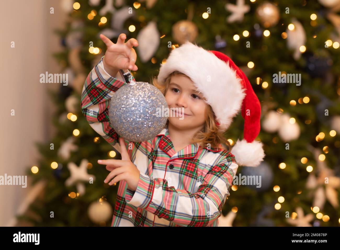 Happy funny child in Santa hat near Christmas tree. Christmas and New ...