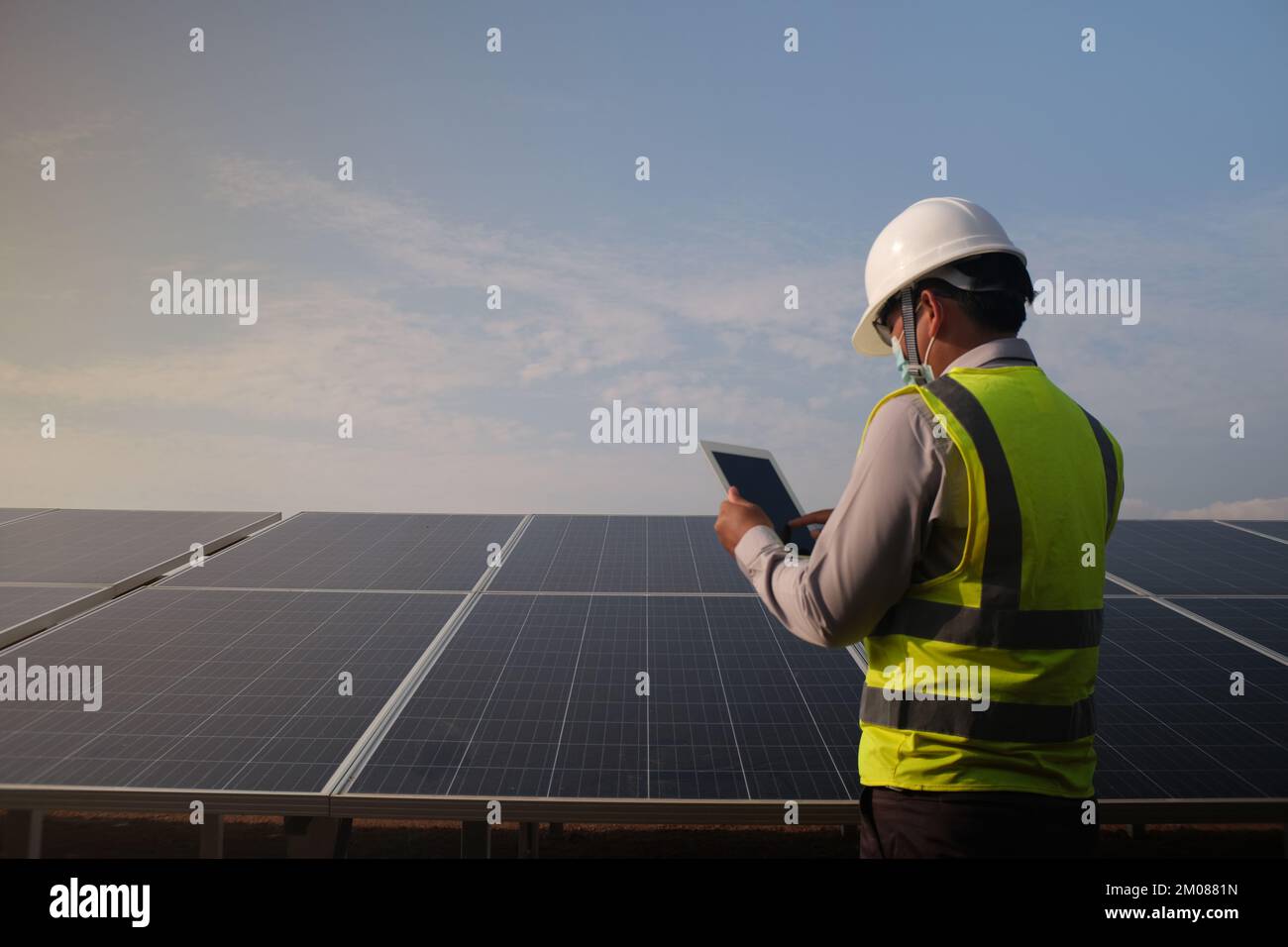 A young Asian engineer wearing a helmet and white mask checks the ...