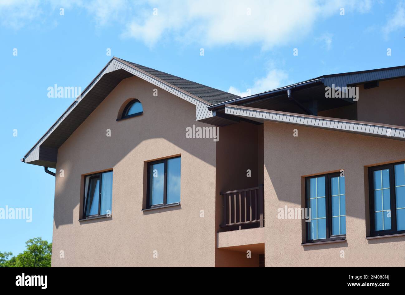 Modern house with asphalt shingles roof, balcony, rain gutter pipeline and soffit boards ...
