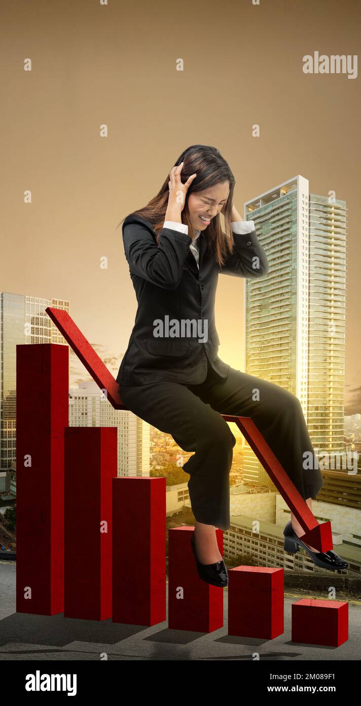 Asian businesswoman sitting on decreasing graph with frustrated ...