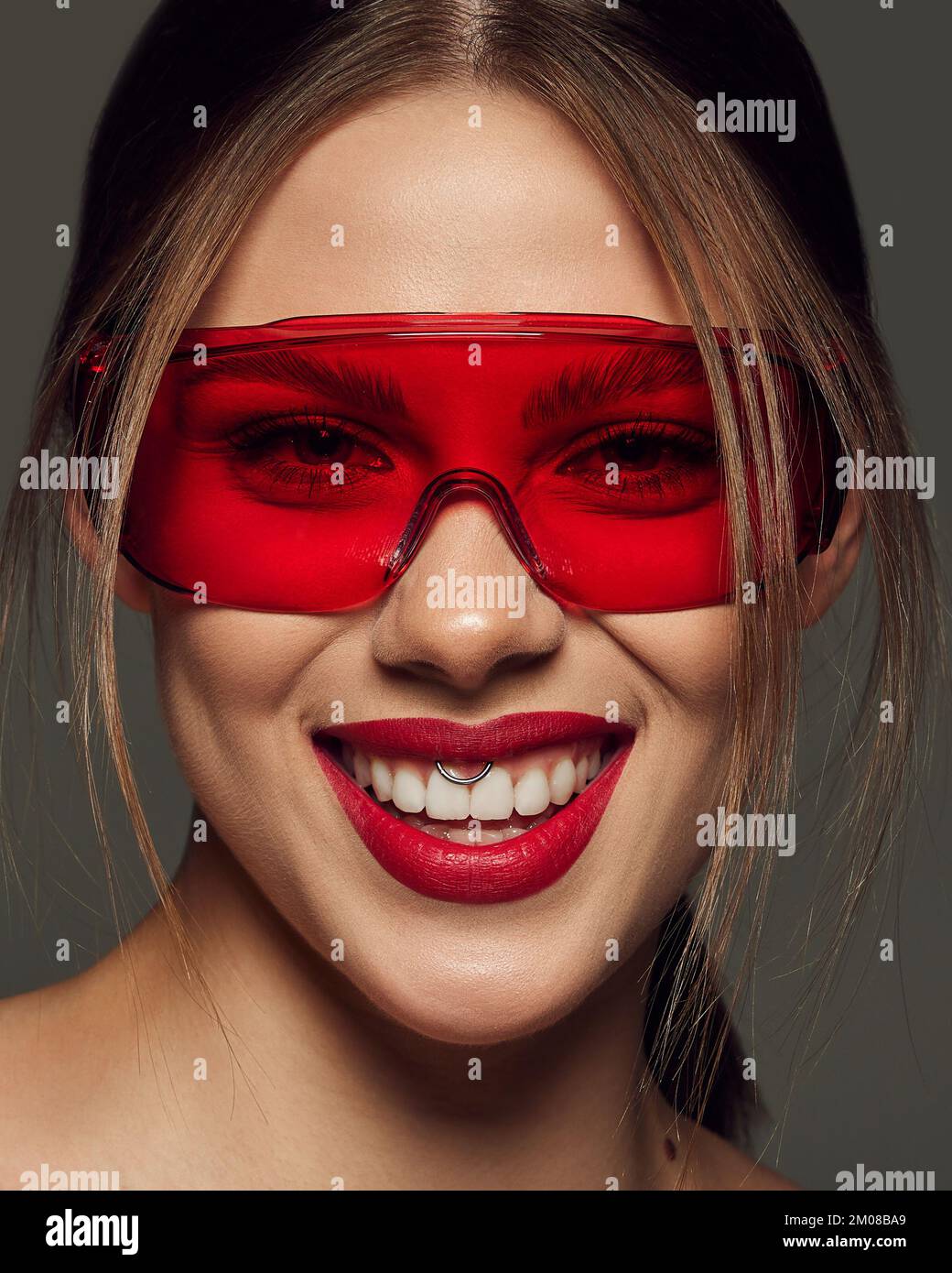 Close Up Portrait Of Beautiful Young Woman In Stylish Red Glasses Smiling Over Dark Grey
